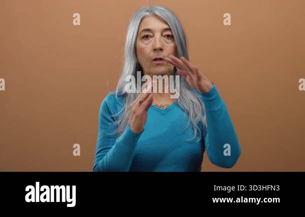 Senior woman with grey hair makes time-out gesture against an isolated ...