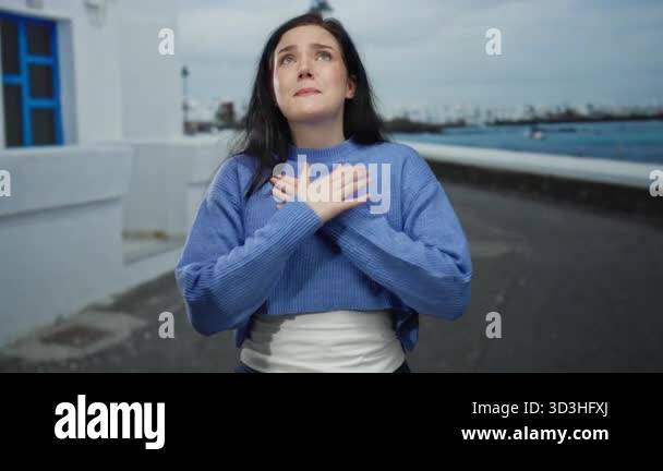 Woman expressing emotion on beach promenade wearing blue sweater ...