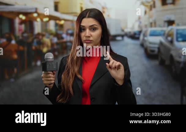 Woman reporter in red and black with microphone pointing finger on busy ...
