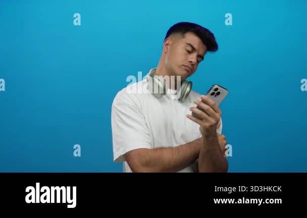 Young man with headphones and smartphone gazing thoughtfully against ...