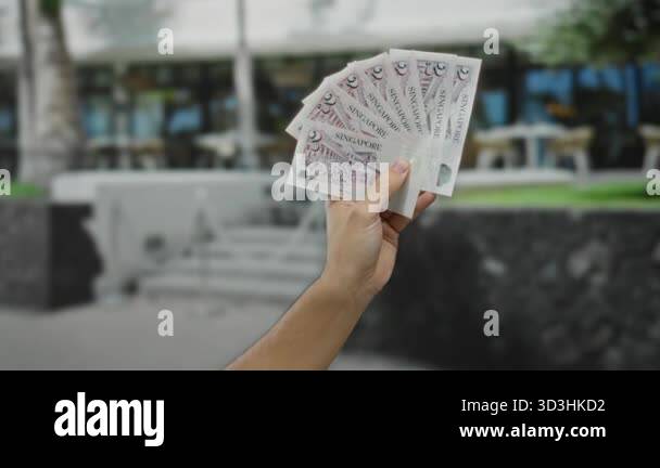 Caucasian man holding singaporean dollars on a city street ...