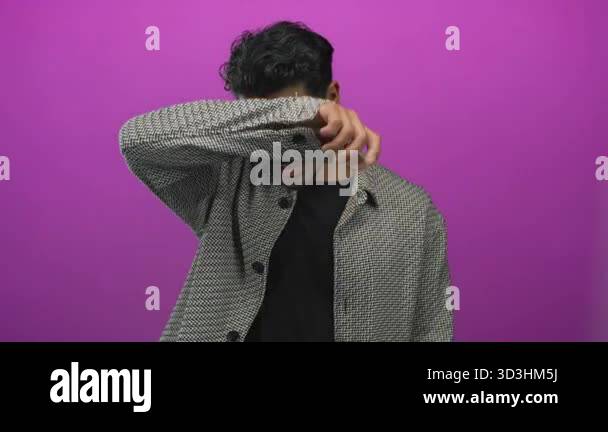 Young hispanic man in herringbone jacket wipes sweat from forehead over ...