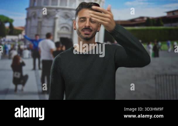 Young hispanic man poses in front of the historic leaning tower of pisa ...