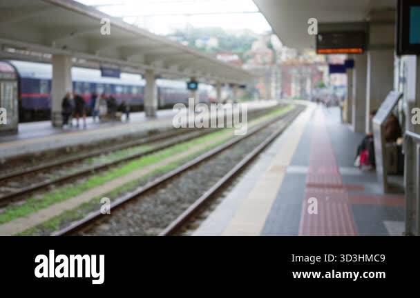Train station scene with blurred background shows people waiting on ...