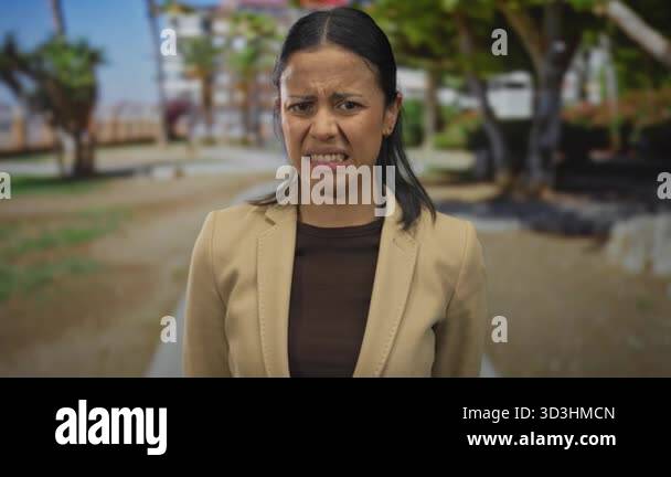 Hispanic woman outdoors in a park displaying disgust with greenery and ...
