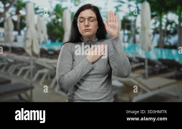 Woman making oath gesture by swimming pool setting with a serious ...