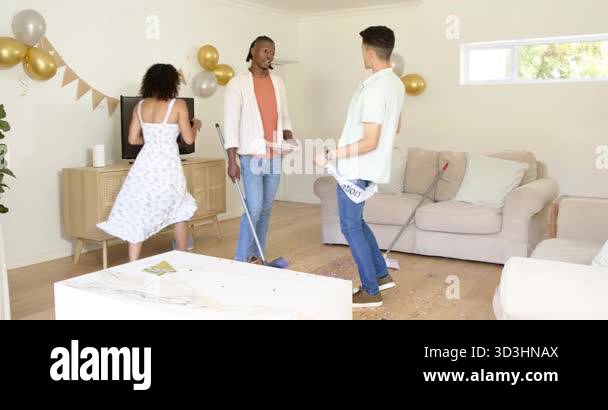 Diverse friends cleaning up after party in living room. celebration ...