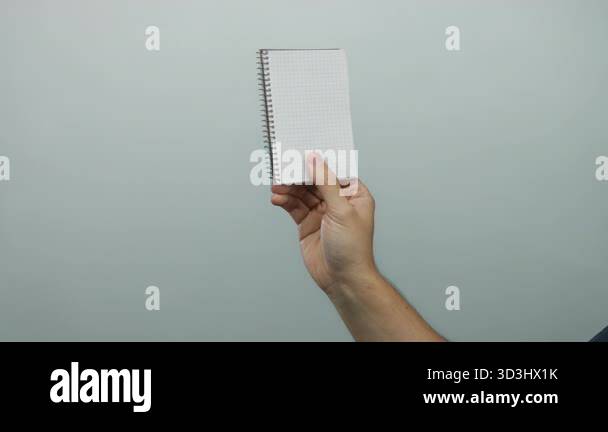 Man's hand holding a spiral notebook against a white isolated ...