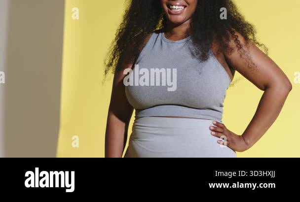 African American woman modeling hands on hips smiling in yellow studio ...