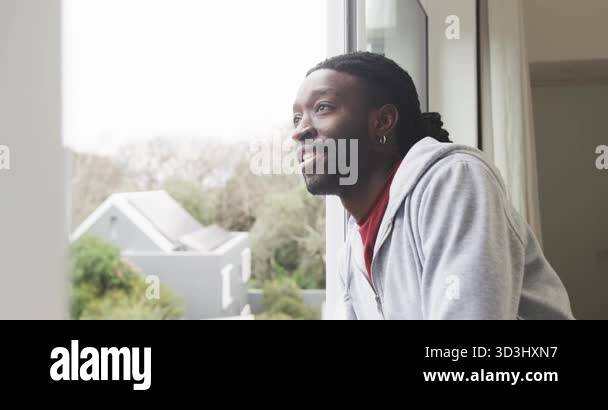 African American man entering, leaning on window sill, extending arms ...