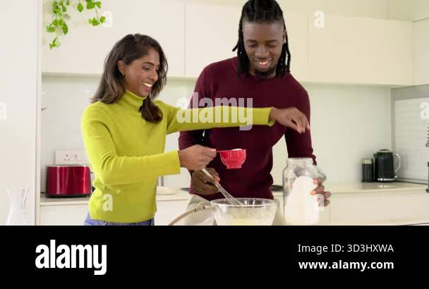 Couple holding cup, pouring milk, sifting flour and whisking for ...