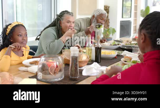 Family eating at dining table, camera panning right, teenage girl ...