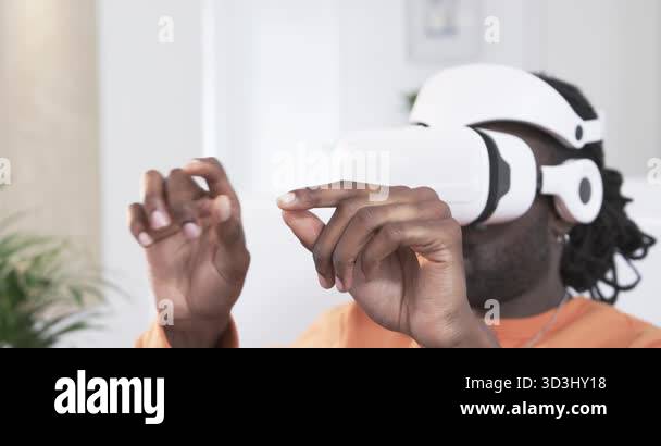 African American male wearing VR headset manipulating controls in ...