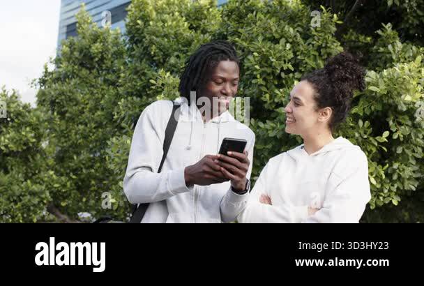 Diverse friends tapping smartphone and sharing funny content beside ...