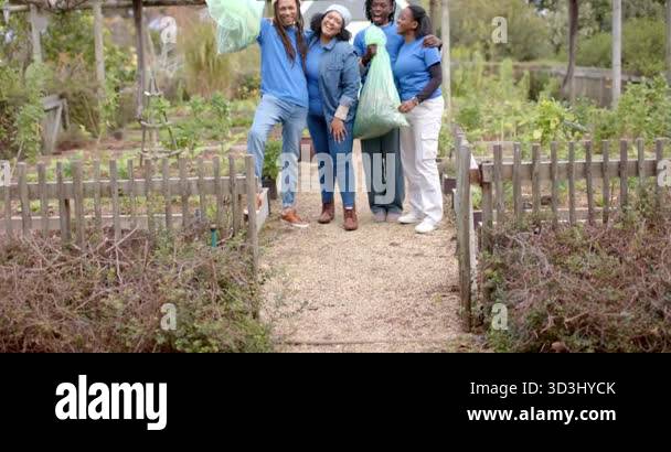 Camera tilting up showing diverse gardeners entering community garden ...