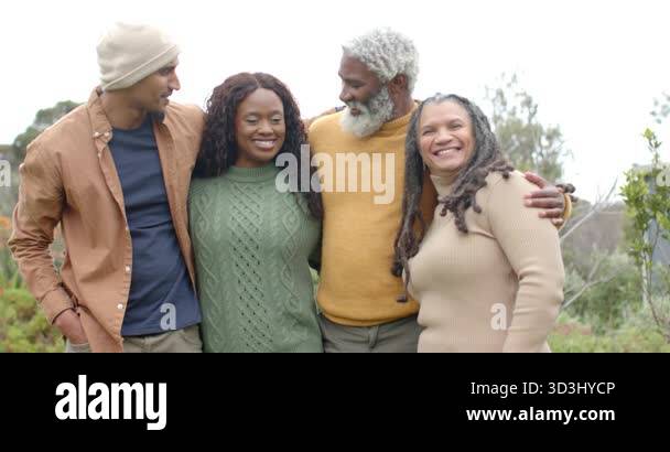 Diverse family exchanging smiles, leaning and laughing in garden ...