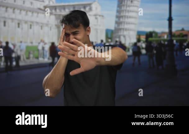 Young hispanic man gestures stop in front of pisa tower in italy while ...