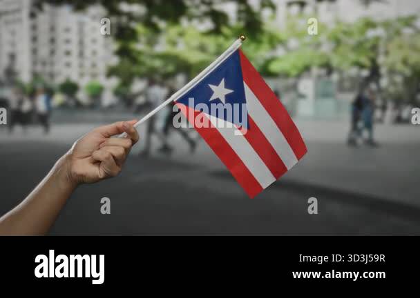 Hand holding puerto rican flag in urban street setting with blurred ...