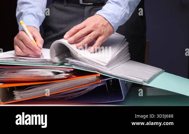 Business persons hands busy writing on a document while managing a ...