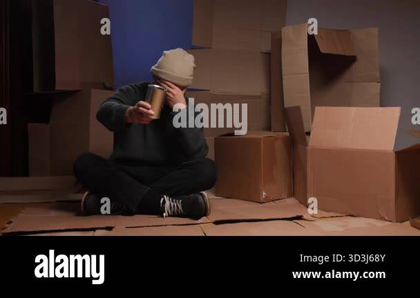 Homeless man with head in hand, wearing a beanie and dark clothing ...
