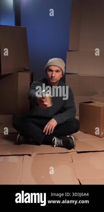 vertical video Man experiencing homelessness sitting on cardboard boxes ...