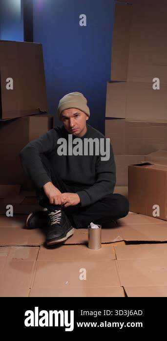 vertical video Homeless man sitting on the floor surrounded by ...
