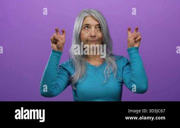 Woman with grey hair making air quotes poses against isolated purple ...