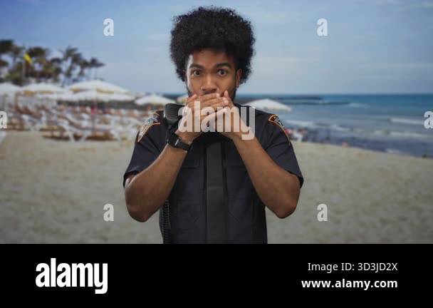 Police officer in uniform stands surprised on a sunny beach with the ...