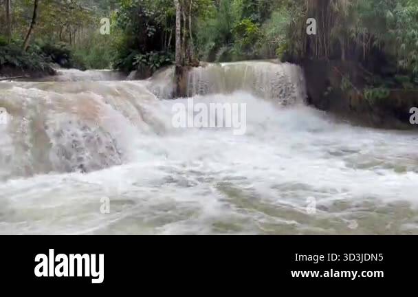 Powerful tropical waterfall flowing through lush green jungle, with ...
