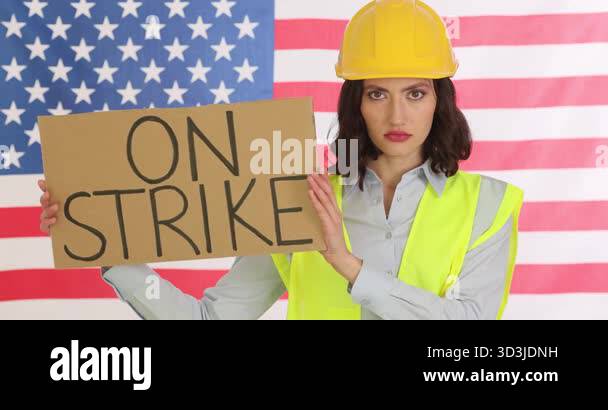 Woman construction worker in hard hat raises On Strike cardboard sign ...