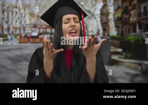 Woman in graduation gown expressing frustration in an urban street ...