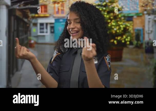 Hispanic police officer in uniform with curly hair flips middle finger ...