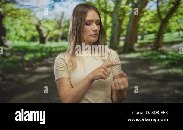Woman in park counting fingers, blonde and contemplative, surrounded by ...