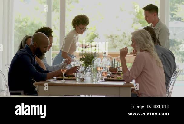 Triggered by server bringing tray, diverse friends sharing meal passing ...