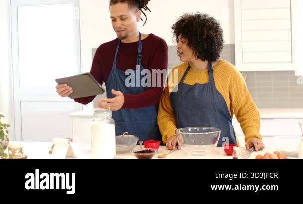 Cooking couple seeing recipe alert tablet, scrolling instructions and ...