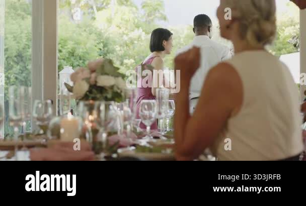 Diverse friends following host greeting and taking seats at dining ...