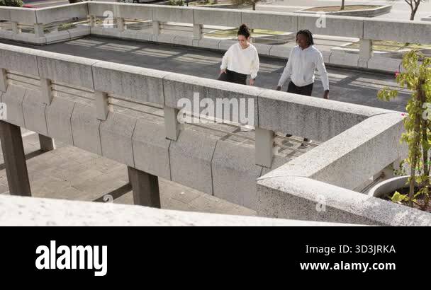 Reaching ramp, Diverse friends stopping to sit on ledge by railing and ...