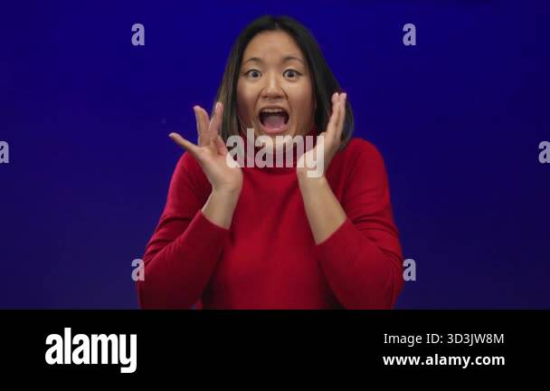 Woman expressing excitement against solid blue background showing ...