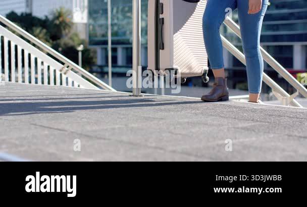 Seeing ramp, woman pulling suitcase climbing ramp toward building ...