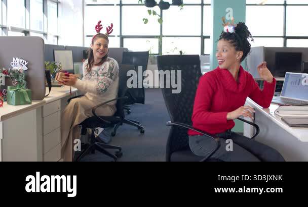 Female coworkers sharing smiles, exchanging wrapped gift box across ...