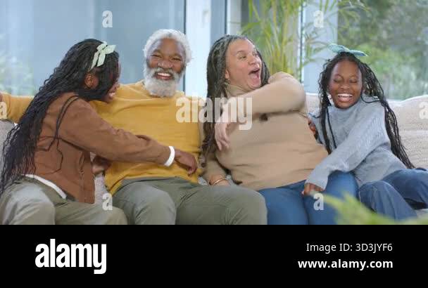 Diverse family hugging on gray couch in living room after ...