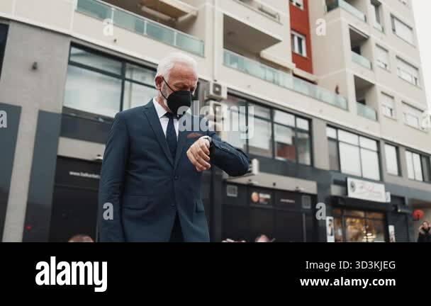 Elderly businessman wearing a protective face mask while hailing a taxi ...