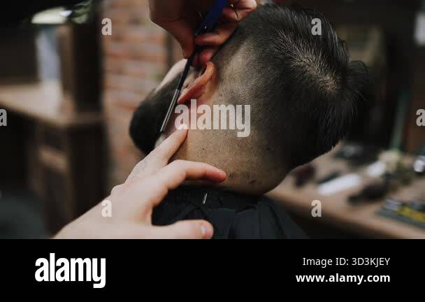 Professional barber precisely trimming a man's haircut with straight ...