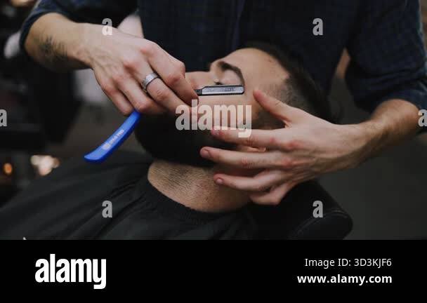 Professional barber precisely trimming a man's haircut with straight ...