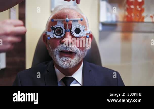 Professional optometrist examining a senior patient's vision with a ...