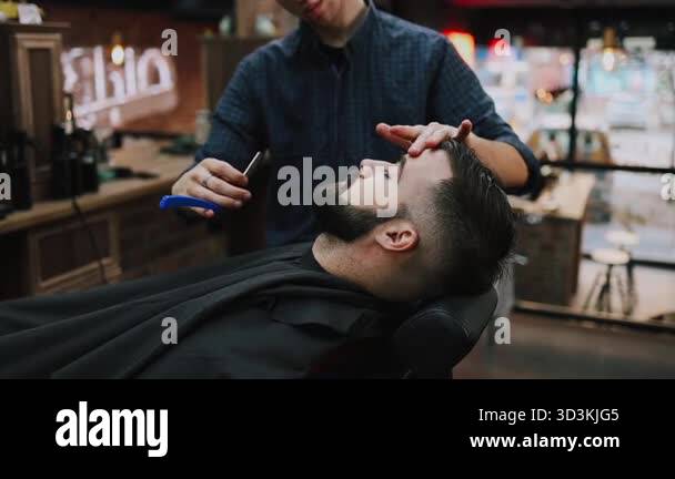 Professional barber precisely trimming a man's haircut with straight ...