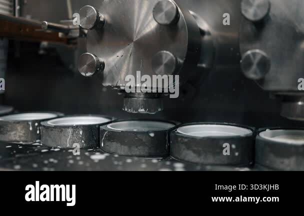 Robotic machine filling plastic cups with creamy yogurt on an ...