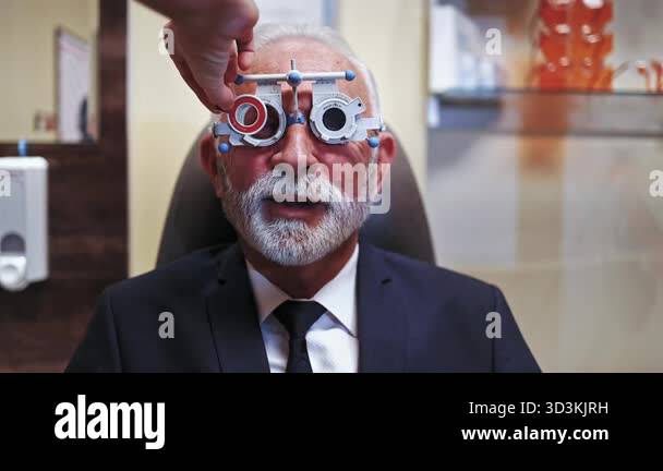 Professional optometrist examining a senior patient's vision with a ...