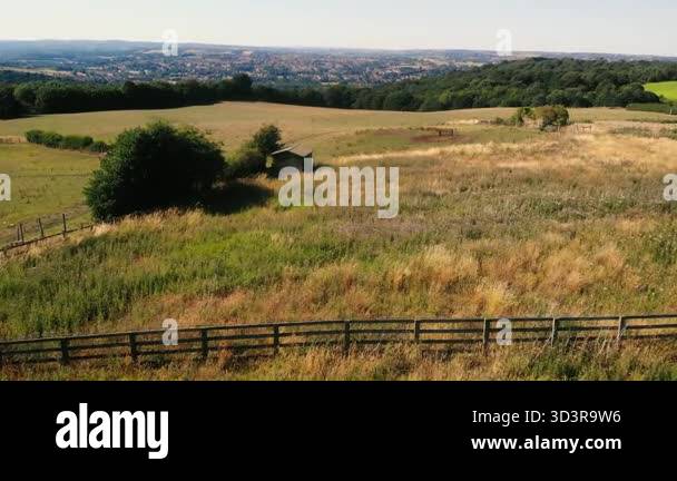 Farmland rugged countryside with cow shed in Dewsbury wide zoom aerial ...