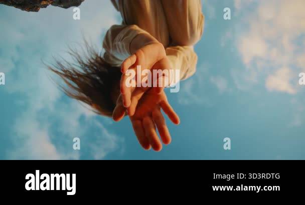 Hands reaching toward the sky framed by rocky edge during dance ...